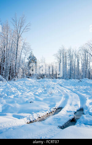 Snow covered dirt road through an empty field with storm clouds brewing ...
