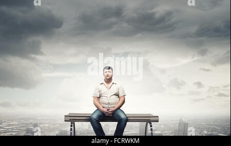 Fat man sitting on bench with his back and pointing away with finger ...