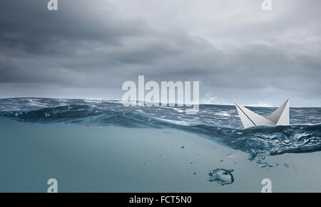 Boat made of paper sinking in blue water surface Stock Photo - Alamy