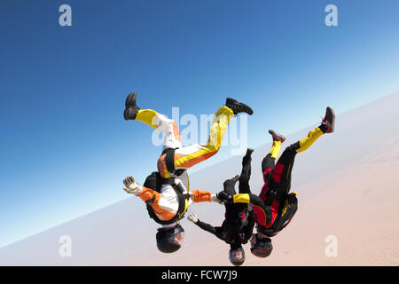 This freefly skydiving team is holding hand together in a head-down ...