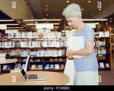 Elderly lady standing next to table with laptop Stock Photo - Alamy