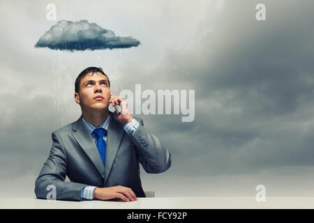 Businessman sitting under rain talking on mobile phone Stock Photo - Alamy
