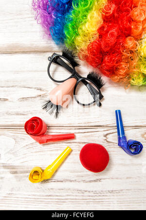 Funny glasses, red clown nose and tie lie on a colored background, like ...