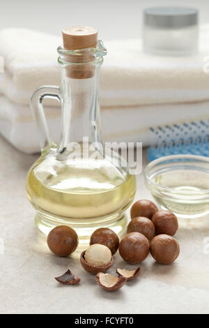 Bottle of natural cosmetics with macadamia nuts on white background ...