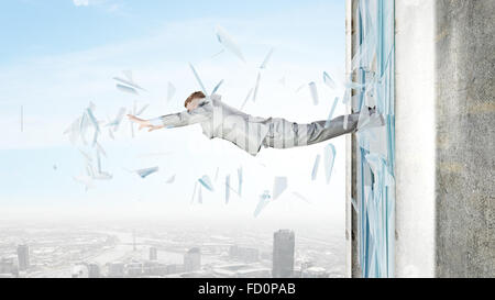 Businessman jumping through glass window of office Stock Photo - Alamy