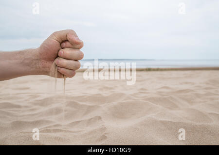 The sand runs through clenched fist. On the background - calm sea Stock ...