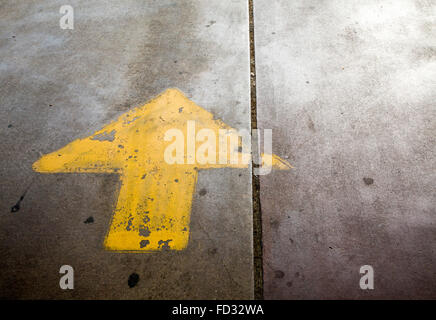 Yellow directional arrow on pavement in parking structure Stock Photo ...