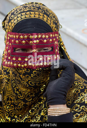 a bandari woman wearing a traditional gold mask called the burqa with a ...