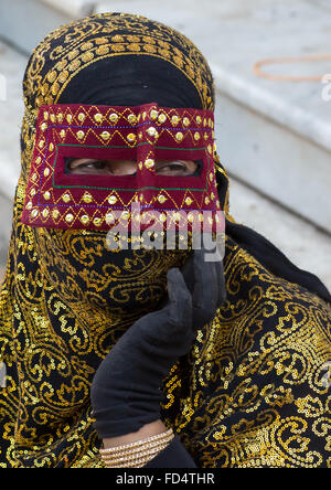 a bandari woman wearing a traditional gold mask called the burqa with a ...