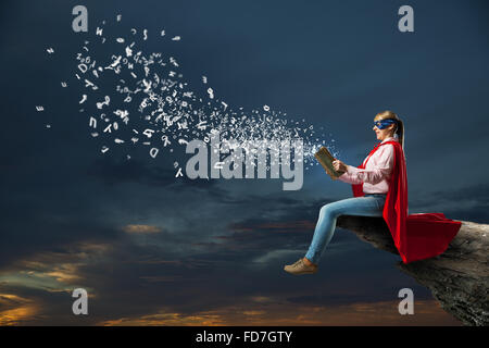 Young woman in super hero costume reading book Stock Photo - Alamy