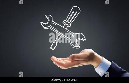 Businessman's hand holding tools over gray background Stock Photo - Alamy