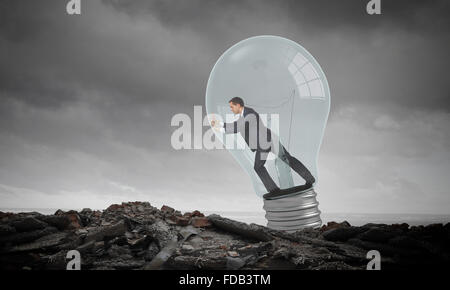 Businessman inside light bulb trying to get out Stock Photo - Alamy