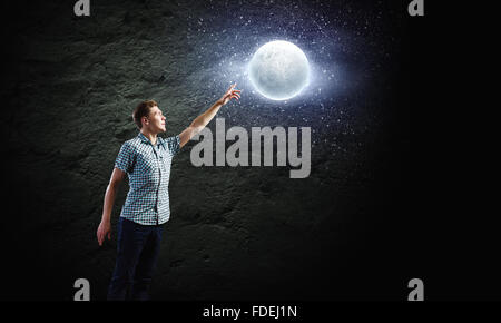 Young man and moon planet against dark background Stock Photo - Alamy