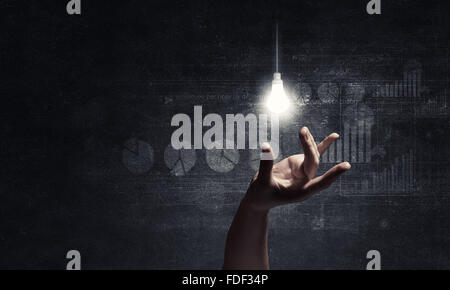 Hand catching glass light bulb with fingers Stock Photo - Alamy