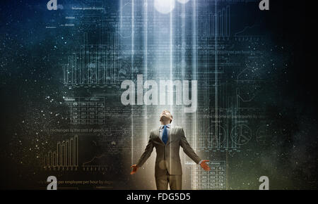 Businessman with hands spread apart standing in light coming from above ...