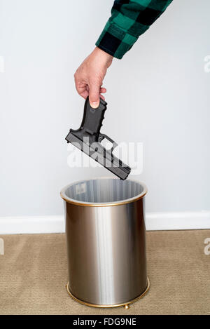 А man hand defiantly disgust , dislike throws the gun in the trash can ...