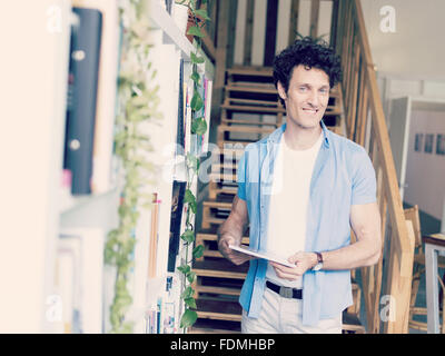 Man with a magazine standing next to bookcase Stock Photo - Alamy