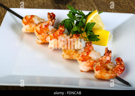 Tiger prawn skewer served sliced lemon and parsley Stock Photo - Alamy