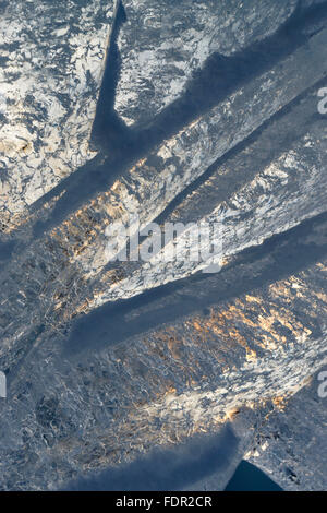 Frozen ice patterns with light filtering through the cracks. The ...