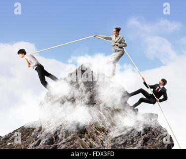 Image of three businesspeople pulling rope atop of mountain Stock Photo ...