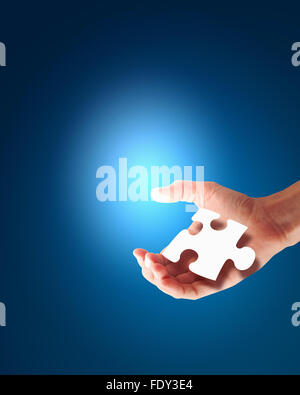 human hand with a blue shining piece of puzzle Stock Photo - Alamy