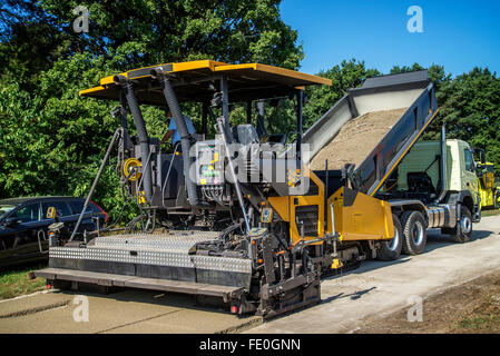 Asphalt paver machine and road construction workers on the road repair ...