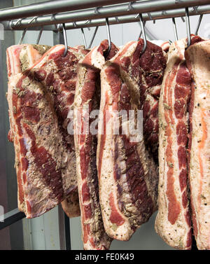 Cuts of meat hanging on hooks at a traditional market butcher shop. Ha ...