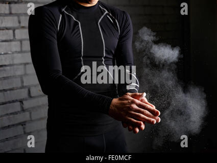 Young man applying chalk powder on hands against dark background Stock ...