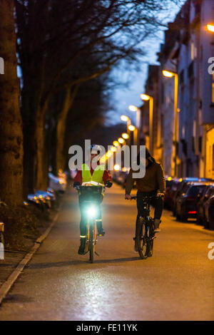 Cyclist driving, at dusk, in a city street, with and without lights and ...