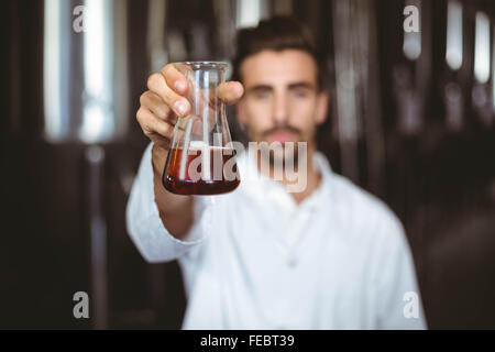 Brewer showing beaker of beer Stock Photo - Alamy
