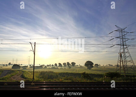 Sun rising behind electricity pylon Stock Photo - Alamy