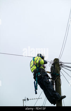 Open reach telecommunications engineer at work up a ladder, he is ...