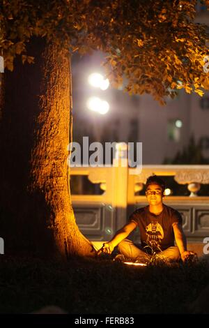 Young man meditating under a tree Stock Photo - Alamy