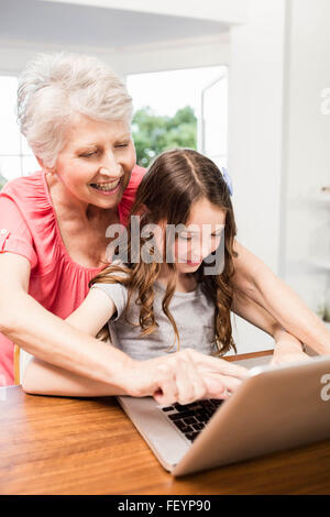 Granddaughter using a computer with her grandmother Stock Photo - Alamy