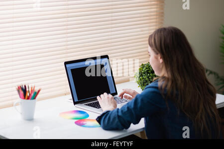 Rear view of hipster businesswoman using laptop at her desk Stock Photo ...