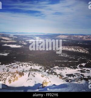 A view of snow-covered Mammoth Mountain ski resort with a tree in the ...