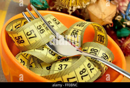 Orange bowl with centimeter and fork on table Stock Photo - Alamy