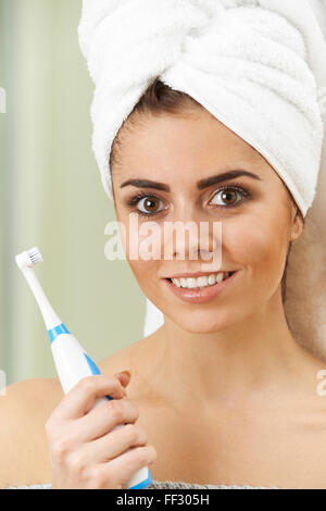 Smiling woman brushing her teeth with towel on her head. A great smile ...