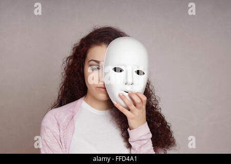 sad girl hiding behind mask Stock Photo - Alamy