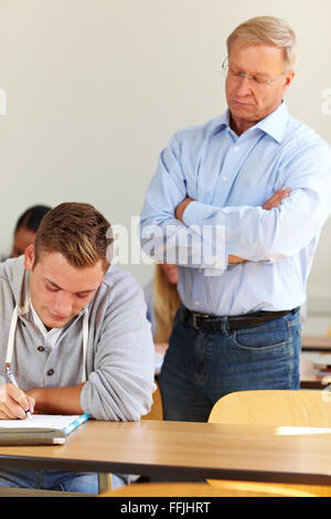 Teacher controlling students work in class Stock Photo - Alamy