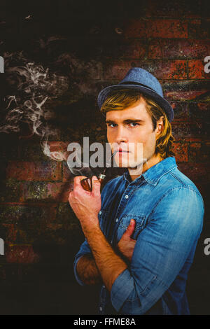 Composite image of serious hipster smoking pipe Stock Photo - Alamy
