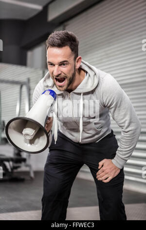 Muscular man shouting on megaphone Stock Photo - Alamy