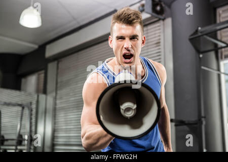 Muscular trainer shouting on megaphone Stock Photo - Alamy