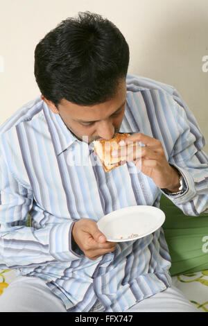 Young man eating a sandwich at home Stock Photo - Alamy