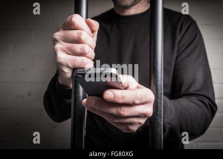A prisoner in prison using a mobile phone behind bars in a cell Stock ...