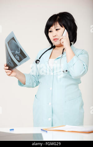 Asian woman medical professional talking phone while reading document ...