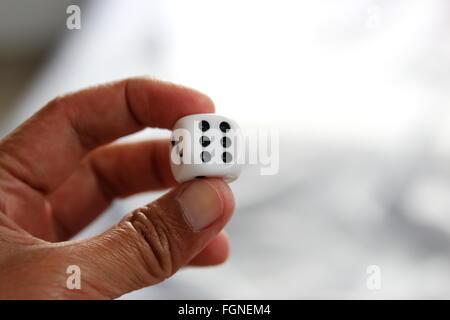 Left hand holding a dice Stock Photo - Alamy