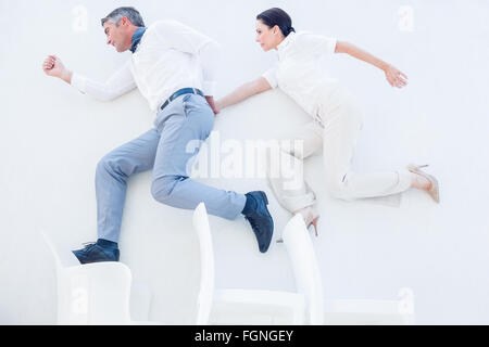 Business partners jumping over chairs Stock Photo - Alamy