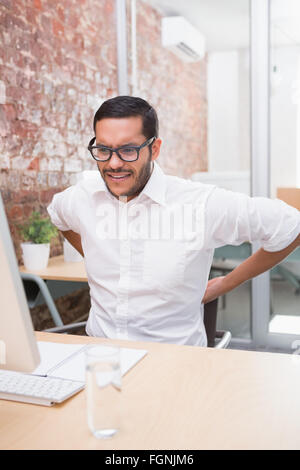 Mixed race businessman rubbing his back in office Stock Photo - Alamy
