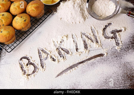 The word Baking written in flour on a dark wood table with freshly ...